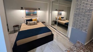 Um quarto moderno com uma cama grande, um guarda-roupa com espelho e um quadro na parede.