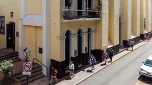Um edifício amarelo com varanda e janelas arqueadas.