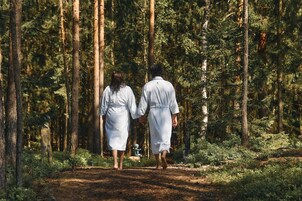 Duas pessoas afastando-se da câmera em uma área arborizada.