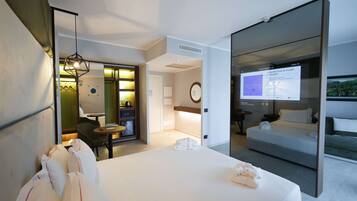 Quarto de hotel moderno com uma cama grande, uma escrivaninha, uma cadeira e uma televisão exibindo um mapa.