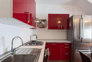 Uma cozinha moderna com eletrodomésticos de aço inoxidável, fogão a gás e armários vermelhos.