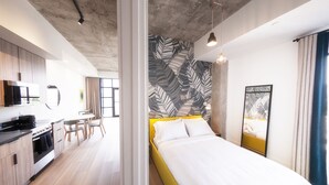 Quarto de hotel moderno com uma cama grande, cozinha compacta e área de jantar.