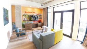 Um hall de hotel moderno com uma janela ampla, um balcão de recepção e um mural colorido.