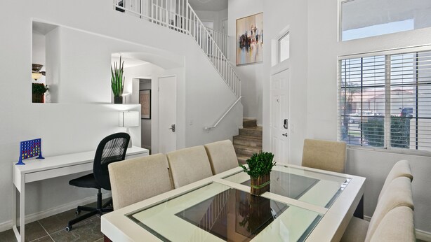 Um interior moderno com área de jantar, escada e vista pela janela.