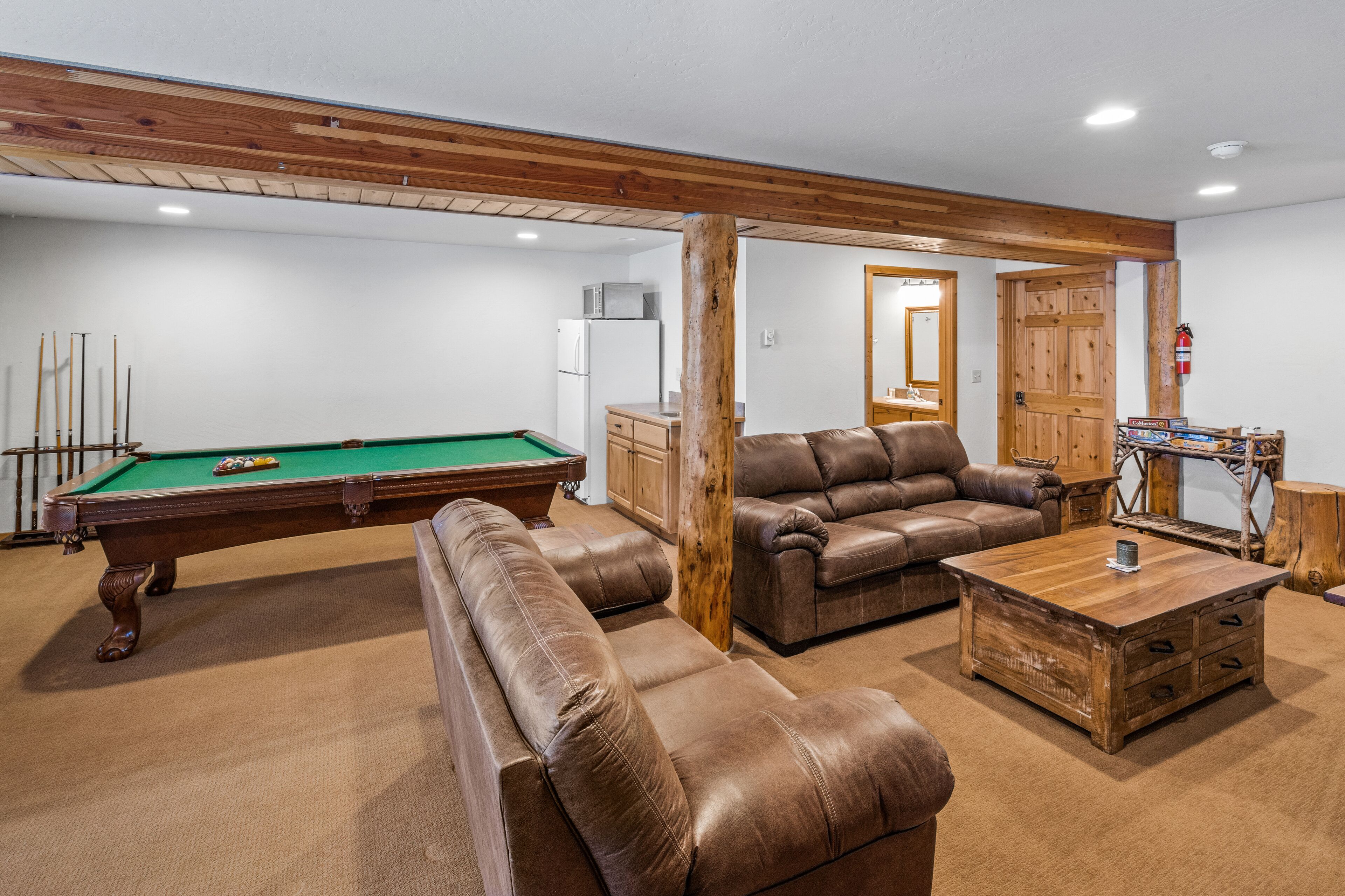 Uma sala de estar aconchegante com mesa de bilhar, sofás de couro e mesa de centro de madeira.
