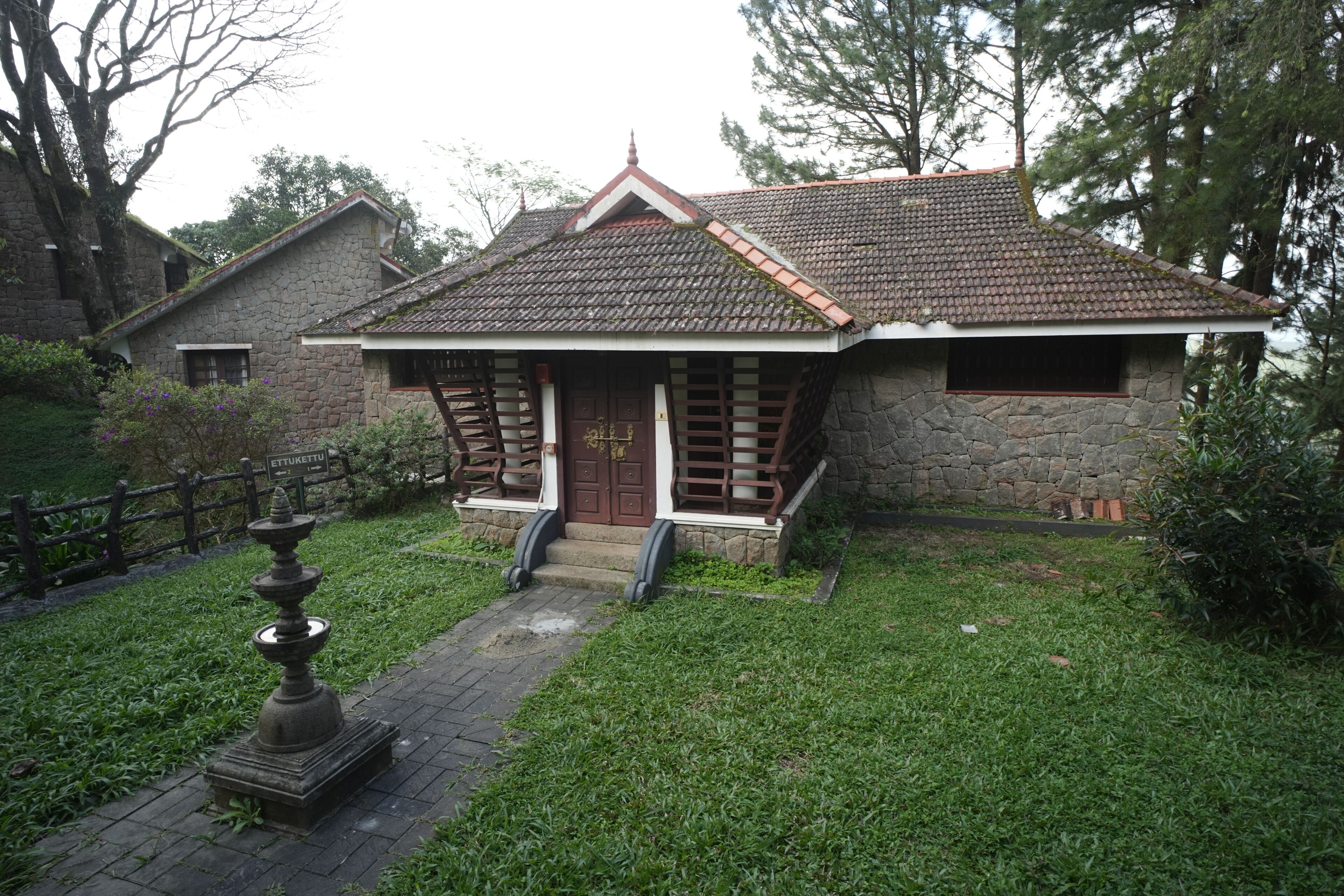 Um edifício de pedra com telhado em telhas, porta de madeira e um pequeno alpendre.