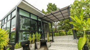 Um edifício moderno com grandes janelas, escadaria coberta e plantas em vasos.