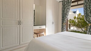 Quarto com cama grande, cómoda de madeira, espelho e janela com cortinas.