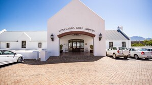 A entrada para Winelands Golf Lodges, com vista desobstruída para o estacionamento e um cenário montanhoso.