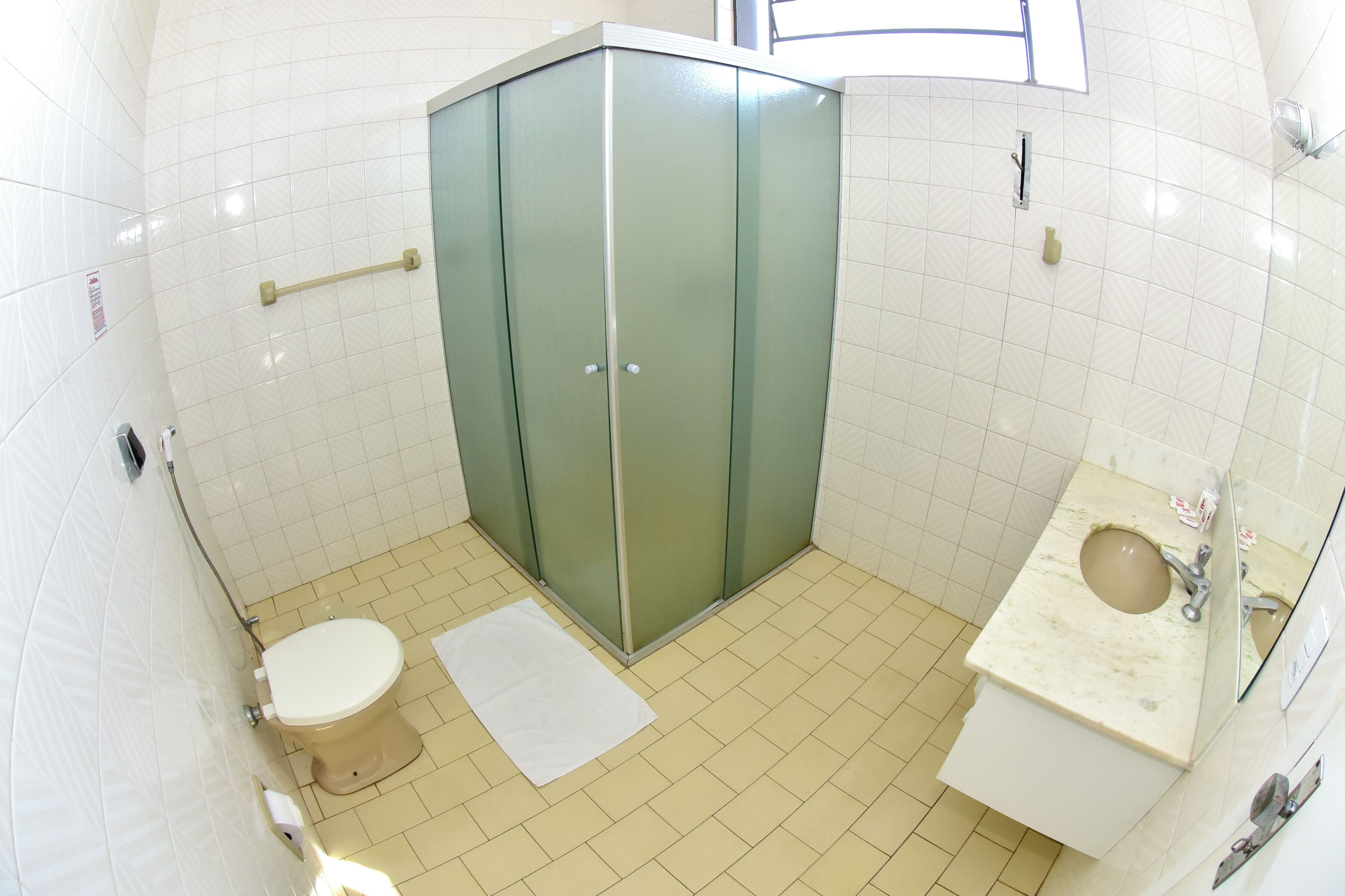 Uma casa de banho com sanita, cabine de duche em vidro e lavatório com espelho.
