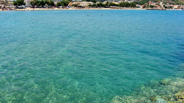Uma cidade costeira com águas azul-claras, uma praia de areia e edifícios ao longo da costa.