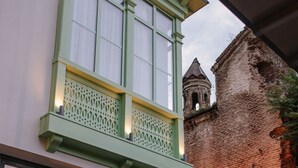 Um edifício com janela emoldurada por verde e parede de tijolos.