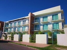Um hotel moderno de vários andares com varandas e céu claro.
