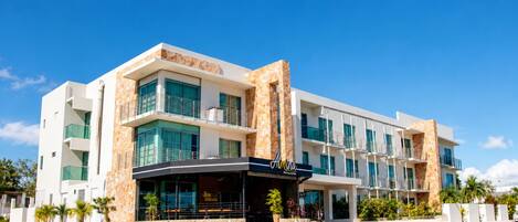 Hotel de vários andares com design moderno, apresentando varandas e um restaurante chamado 'Alina'.