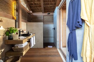 Um banheiro moderno com piso de madeira, pia com espelho, porta-toalhas e área de chuveiro.