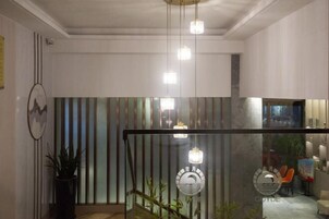Um interior moderno com divisória de vidro, luminárias pendentes e um vaso com planta.