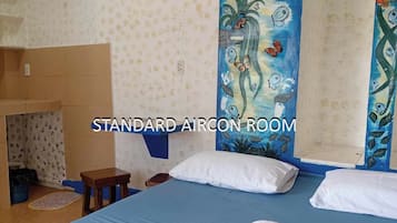 Quarto standard com ar condicionado, cama, almofadas, um quadro e uma escultura de toalha.
