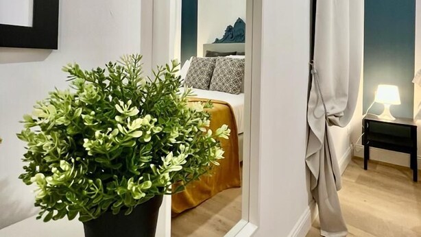 Quarto moderno com cama, mesa de cabeceira e espelho.