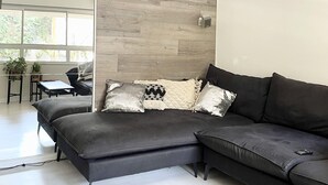 Uma sala de estar moderna com um sofá seccional, uma mesa de centro e uma parede de destaque em madeira.