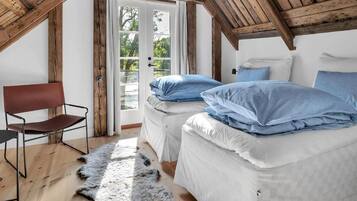 Quarto com duas camas, uma cadeira e porta que dá para área externa.