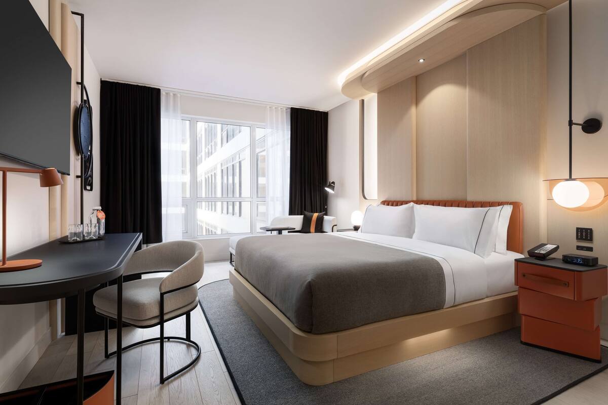 Quarto de hotel moderno com uma cama grande, uma escrivaninha e uma cadeira.