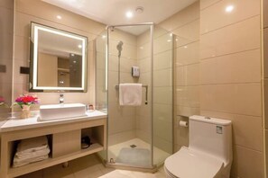 Casa de banho moderna com cabine de duche em vidro, lavatório com espelho e sanita.
