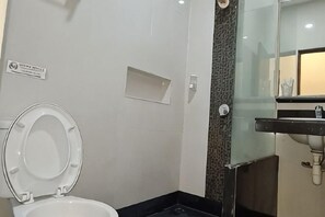 Casa de banho com sanita, chuveiro e lavatório.