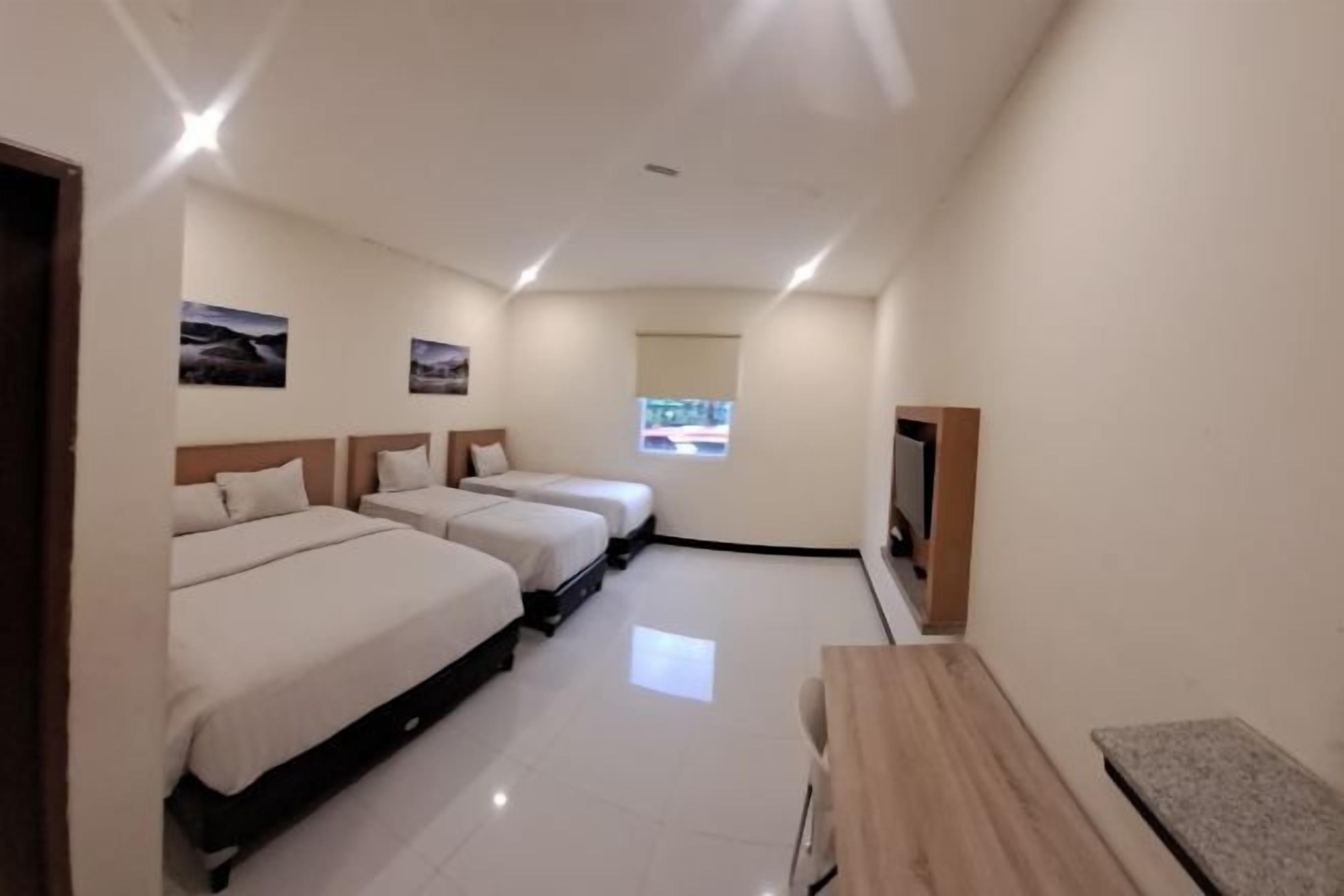 Quarto de hotel com duas camas, uma mesa pequena, televisão e janela.
