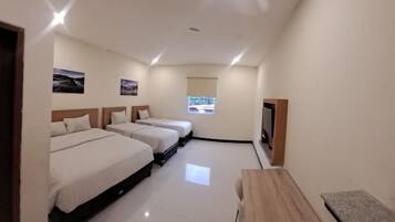 Quarto de hotel com duas camas, uma mesa pequena, televisão e janela.
