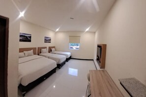 Quarto de hotel com duas camas, uma mesa pequena, televisão e janela.