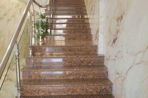 Uma escadaria de mármore com corrimãos de metal, subindo.