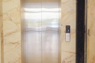 Um elevador com acabamento metálico e painel de controle na parede.
