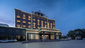 Um hotel moderno com entrada imponente e uma estátua em frente.