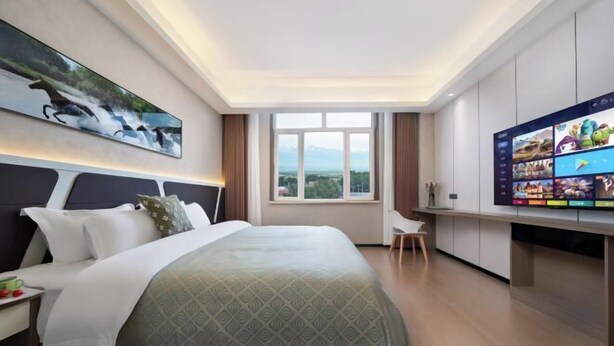 Quarto de hotel com uma cama, uma escrivaninha, uma televisão e uma janela com vista.