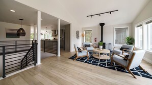 Ampla sala de estar com teto alto, escada e vista para a cozinha.