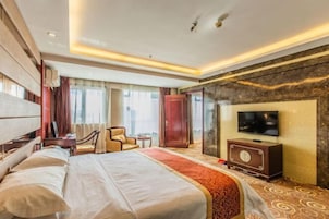 Quarto de hotel com uma cama grande, televisão, escrivaninha e cadeira.