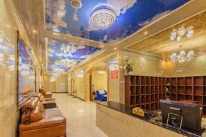 Um hall de hotel com balcão de recepção, área de estar e teto com design de nuvens.