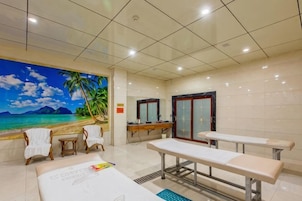 Quarto com mural de praia, balcão de recepção, um banco e área de recepção com balcão e portas de vidro.