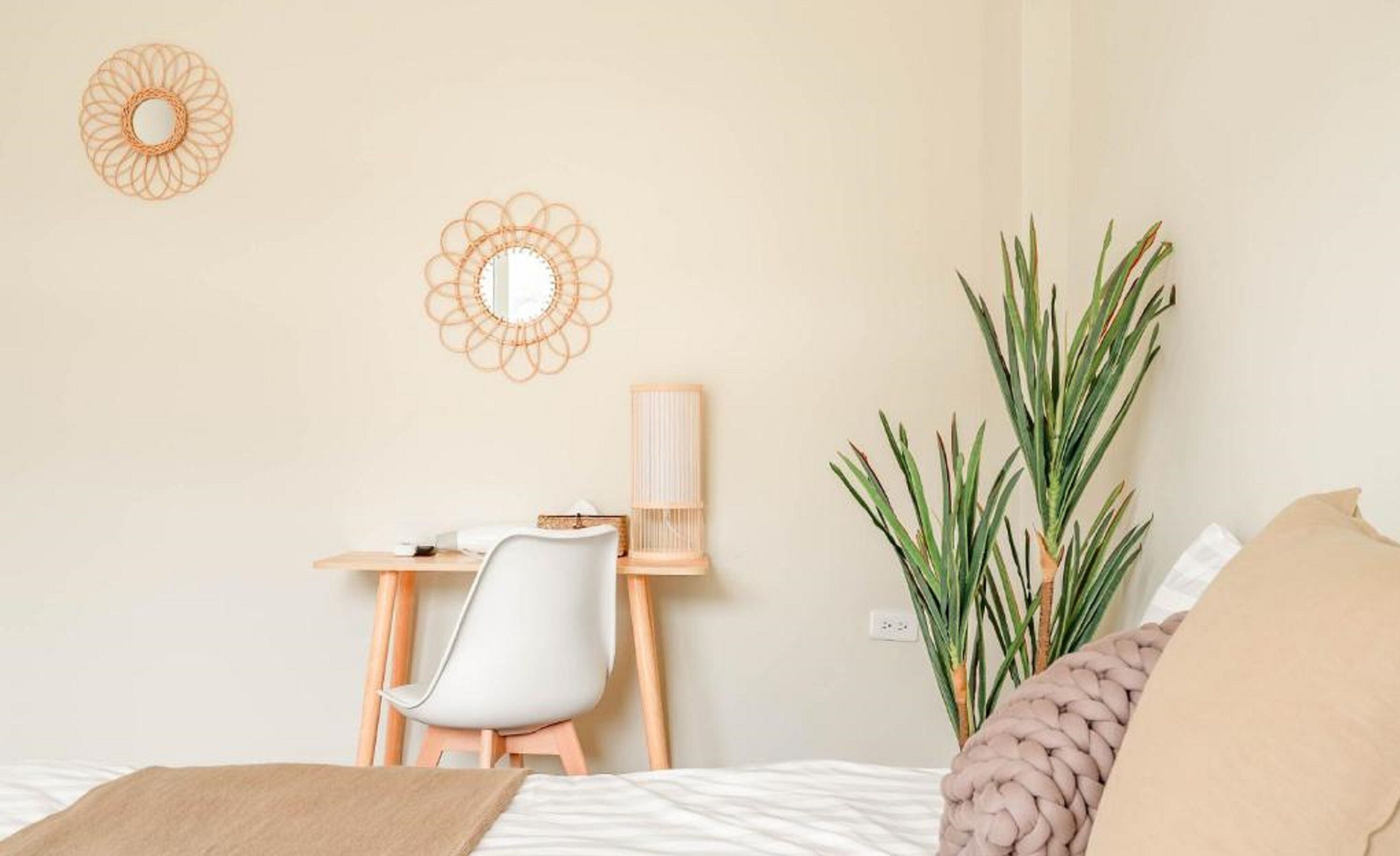 Quarto com cama, escrivaninha, cadeira, mesa de cabeceira, abajur e planta em vaso.