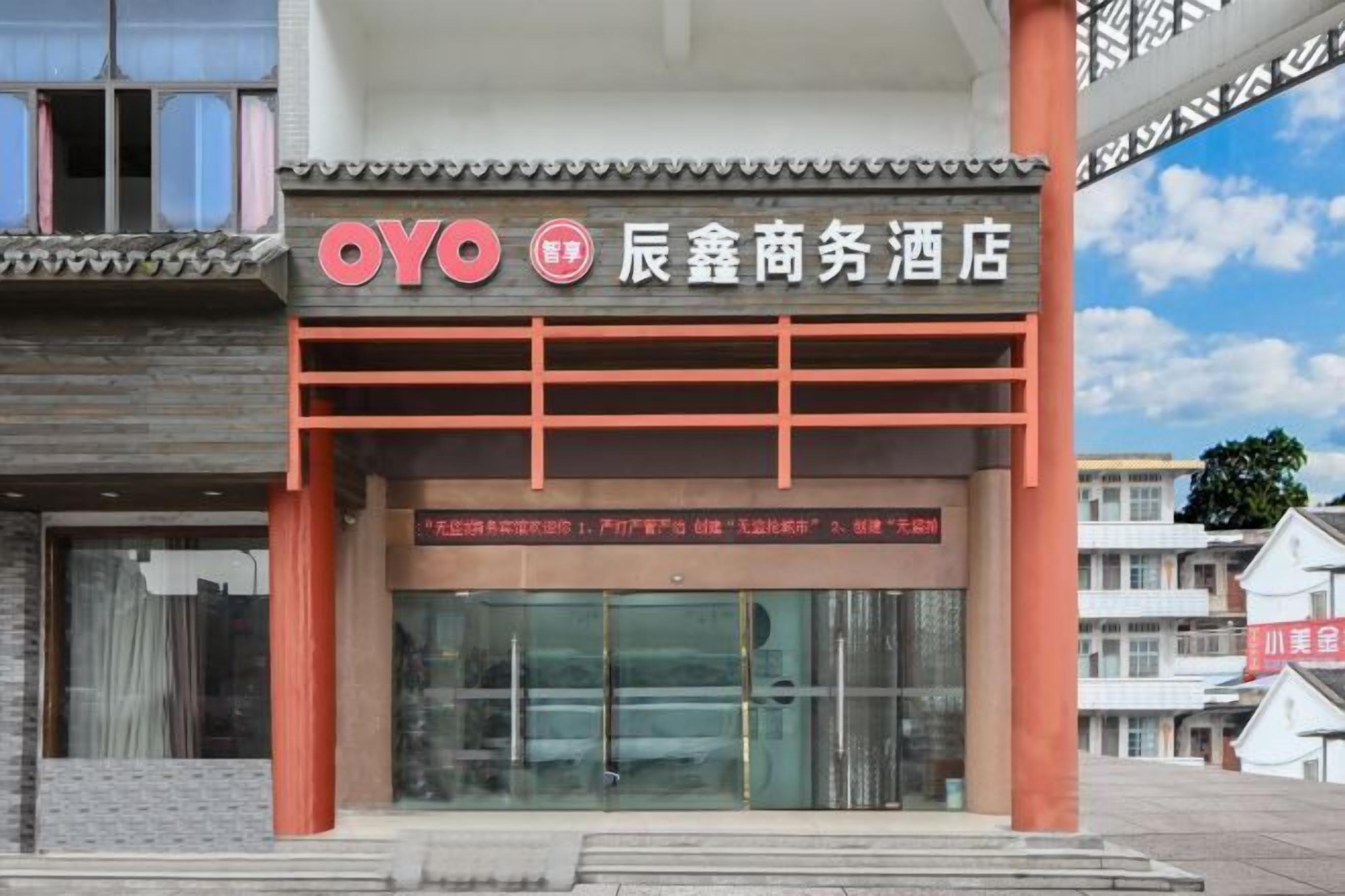 Entrada de um hotel com uma placa indicando "OYO" e "Yin Xin Commercial Hotel".