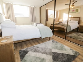 Quarto de hotel com duas camas, piso de madeira, um espelho e vista para o exterior.