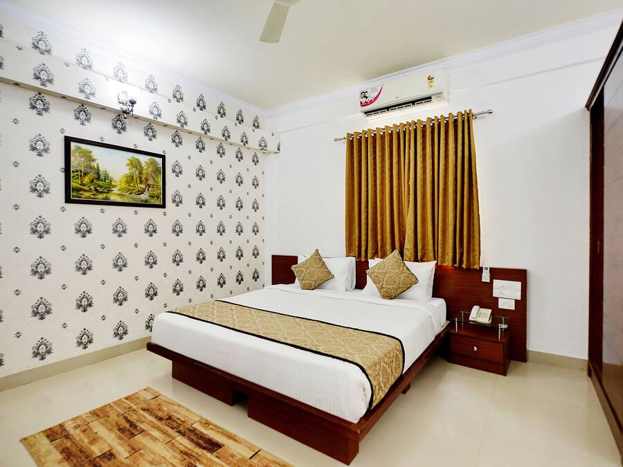 Quarto com cama grande, cabeceira de madeira, mesa de cabeceira, ar condicionado fixado na parede e quadro emoldurado.