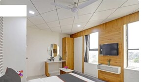 Quarto com cama, escrivaninha, espelho, televisão e janela.