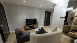 Uma sala de estar moderna com sofá, puf e televisão.