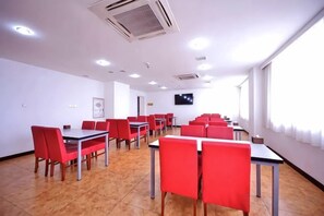 Uma sala de conferências com mesas, cadeiras, uma TV de tela plana e janelas.