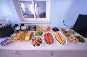 Mesa de buffet com diversos alimentos e uma janela ao fundo.