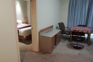Quarto de hotel com uma cama, uma mesa, uma cadeira e uma pequena mesa.