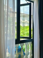 Janela com vista para um edifício e vegetação.