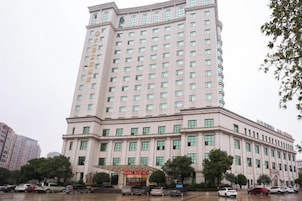 Hotel com vários andares, entrada destacada e estacionamento em frente.