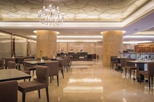 Um saguão de hotel com balcão de recepção, área de estar e um candelabro.